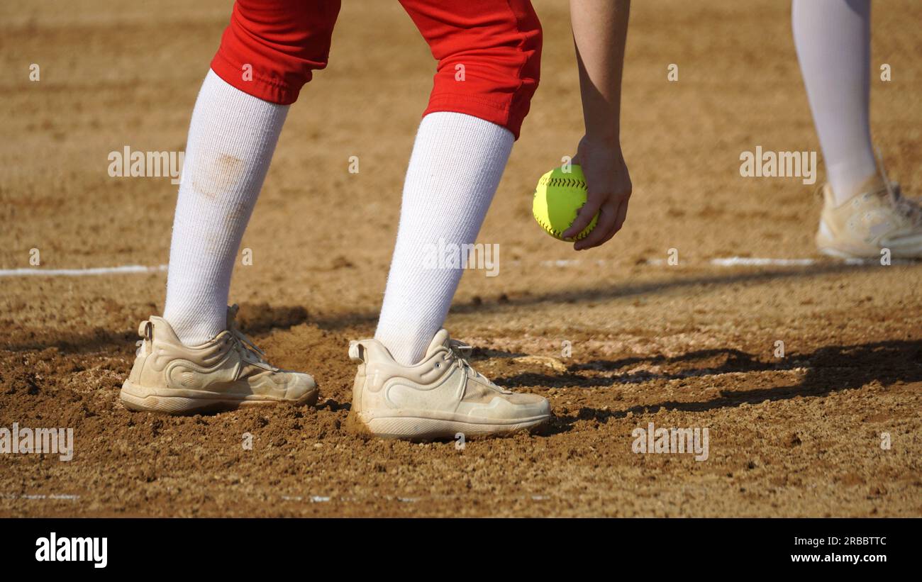 Softball player picks up a ball off the infield and prepares to throw ...