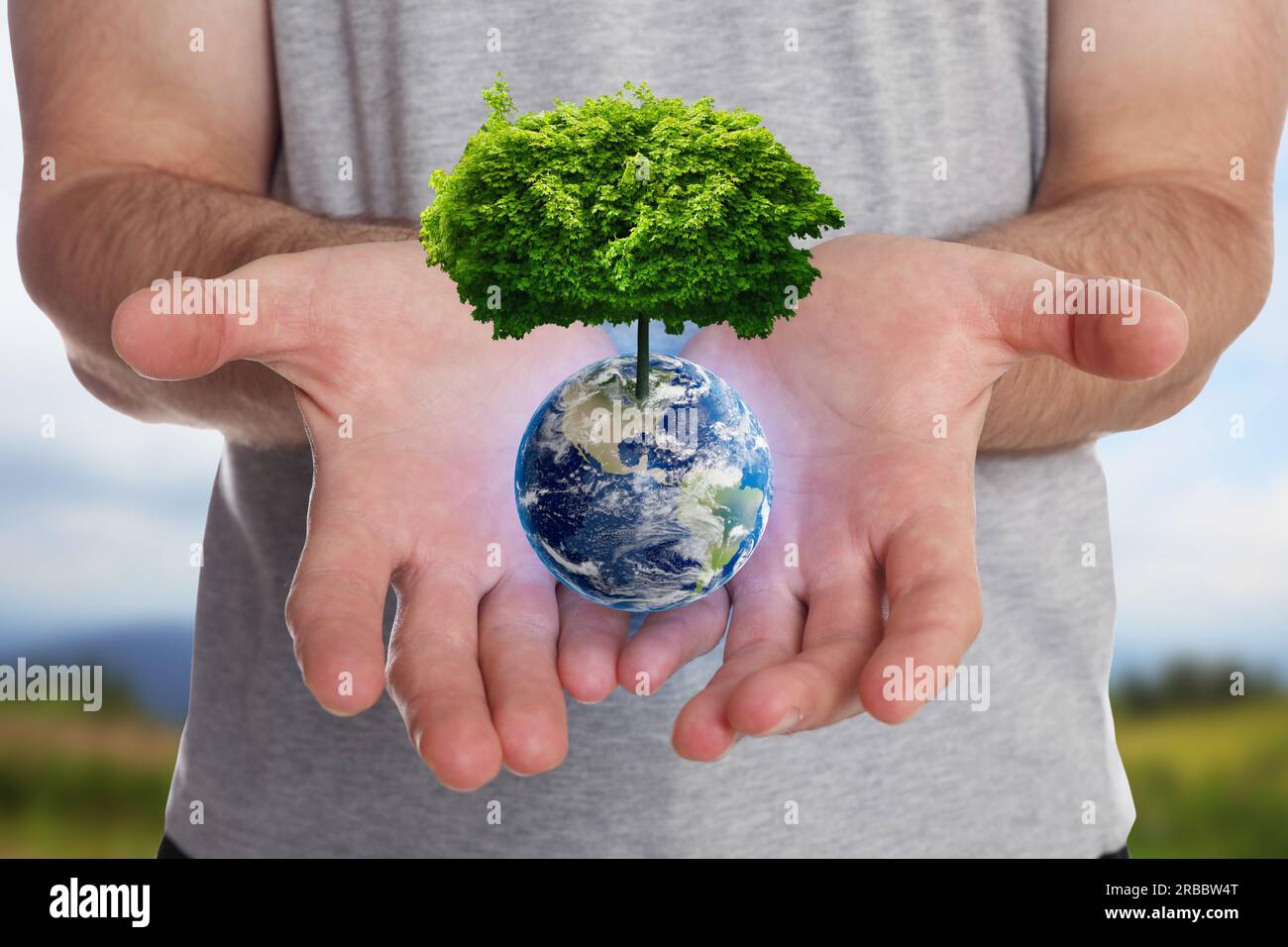 Make Earth green. Man holding globe with tree on top outdoors, closeup ...