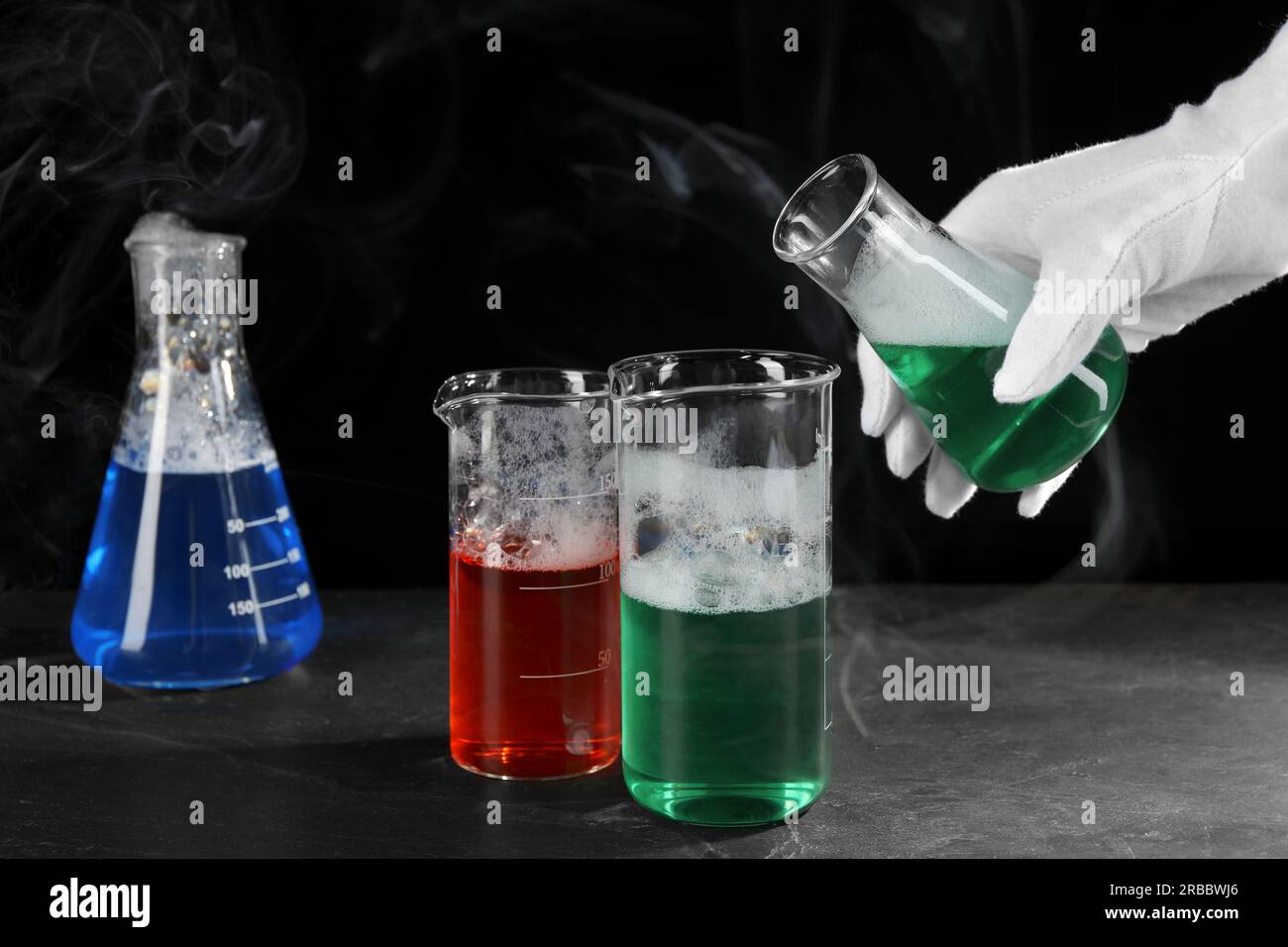 Scientist working with laboratory glassware at black table, closeup ...