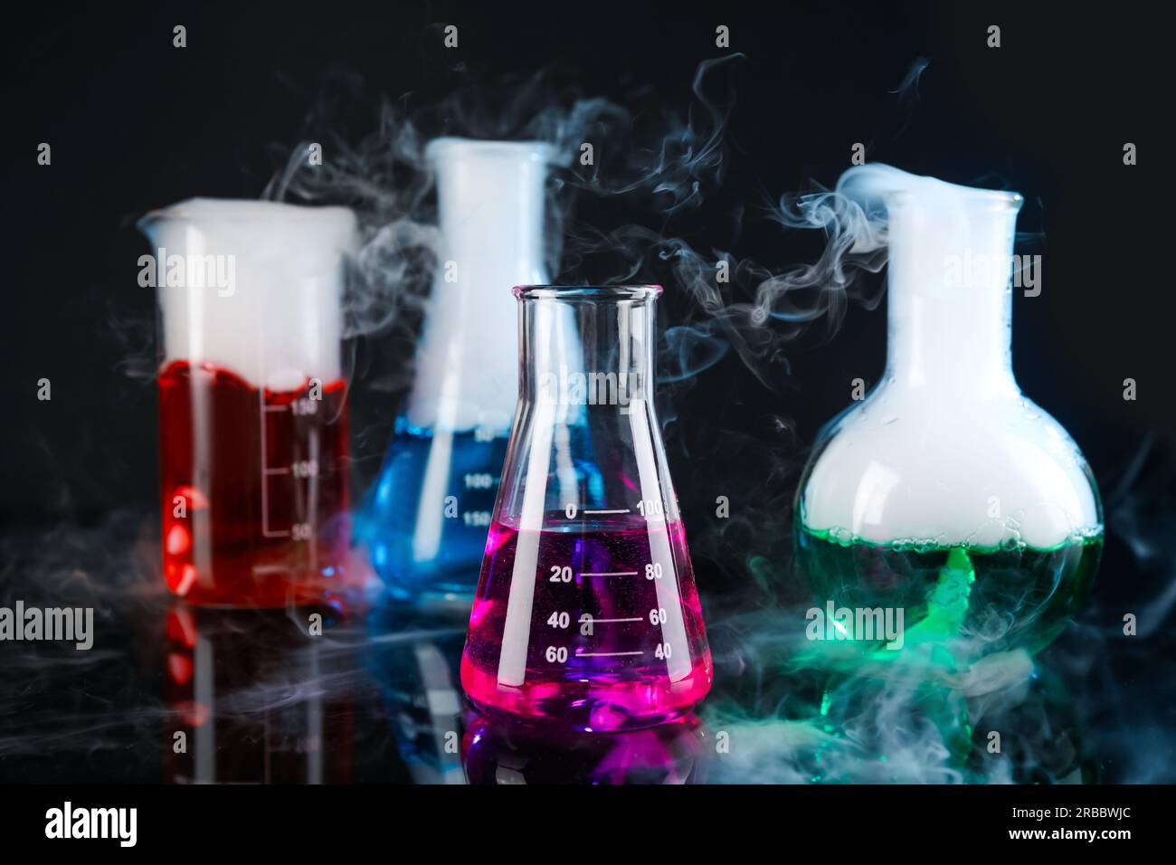 Laboratory glassware with colorful liquids and steam on black ...