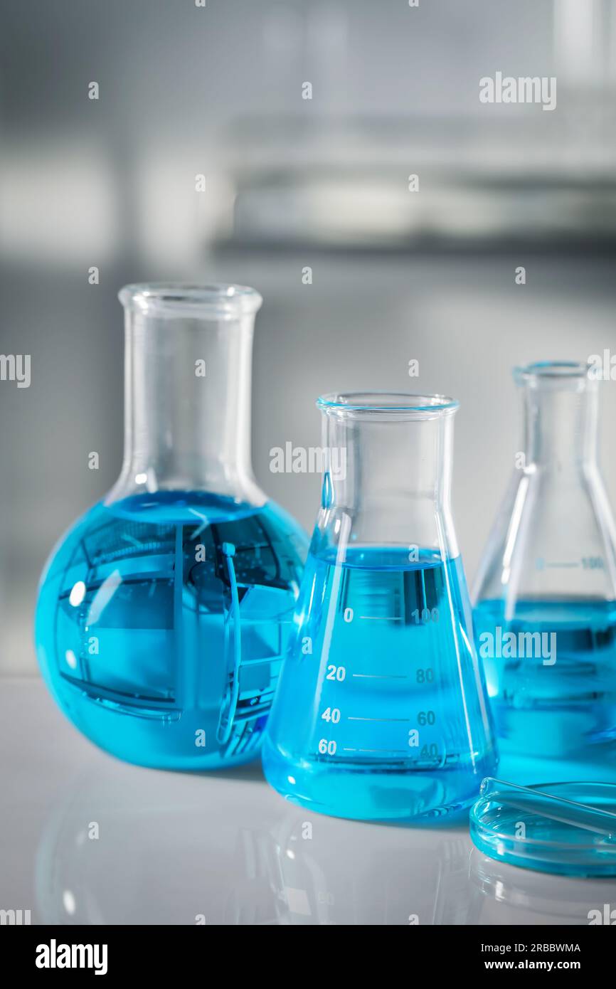 Different glassware with light blue liquid on table in laboratory Stock ...