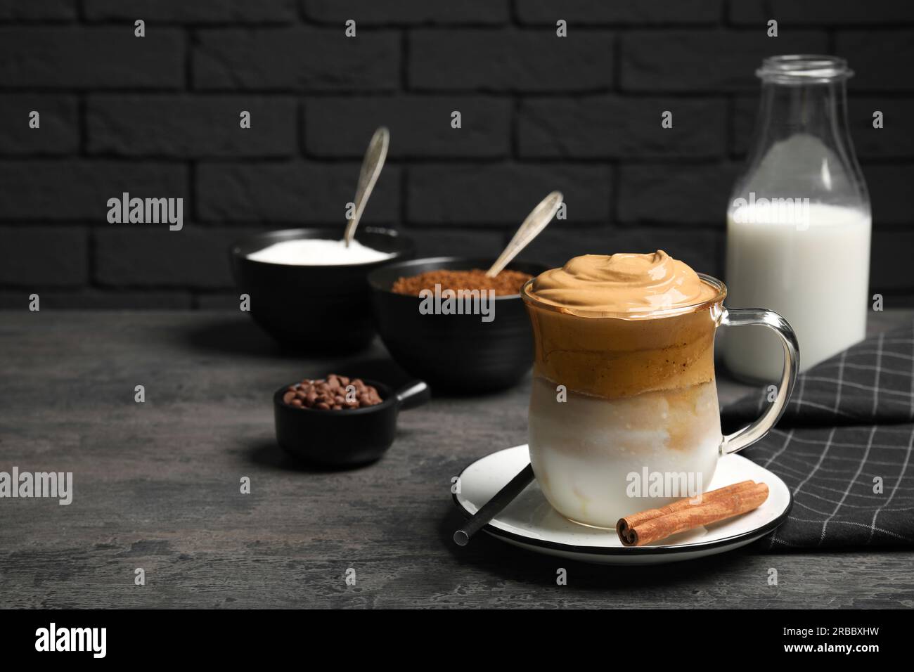 Delicious dalgona coffee and ingredients on grey table. Space for text ...