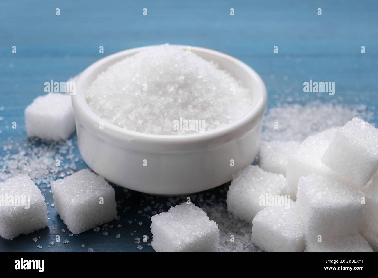 Different types of white sugar on light blue wooden table, closeup ...