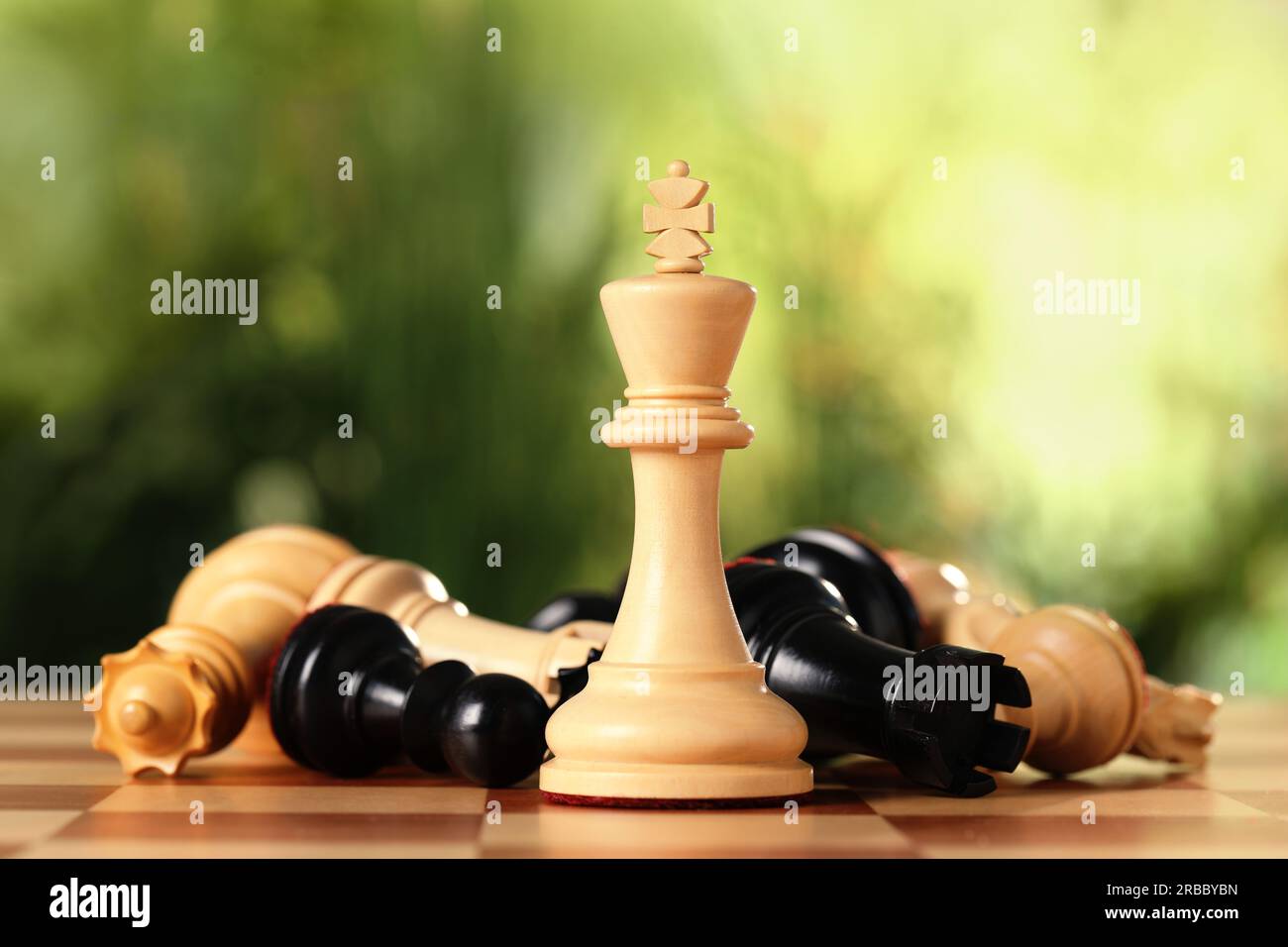Wooden king among fallen chess pieces on game board against blurred ...
