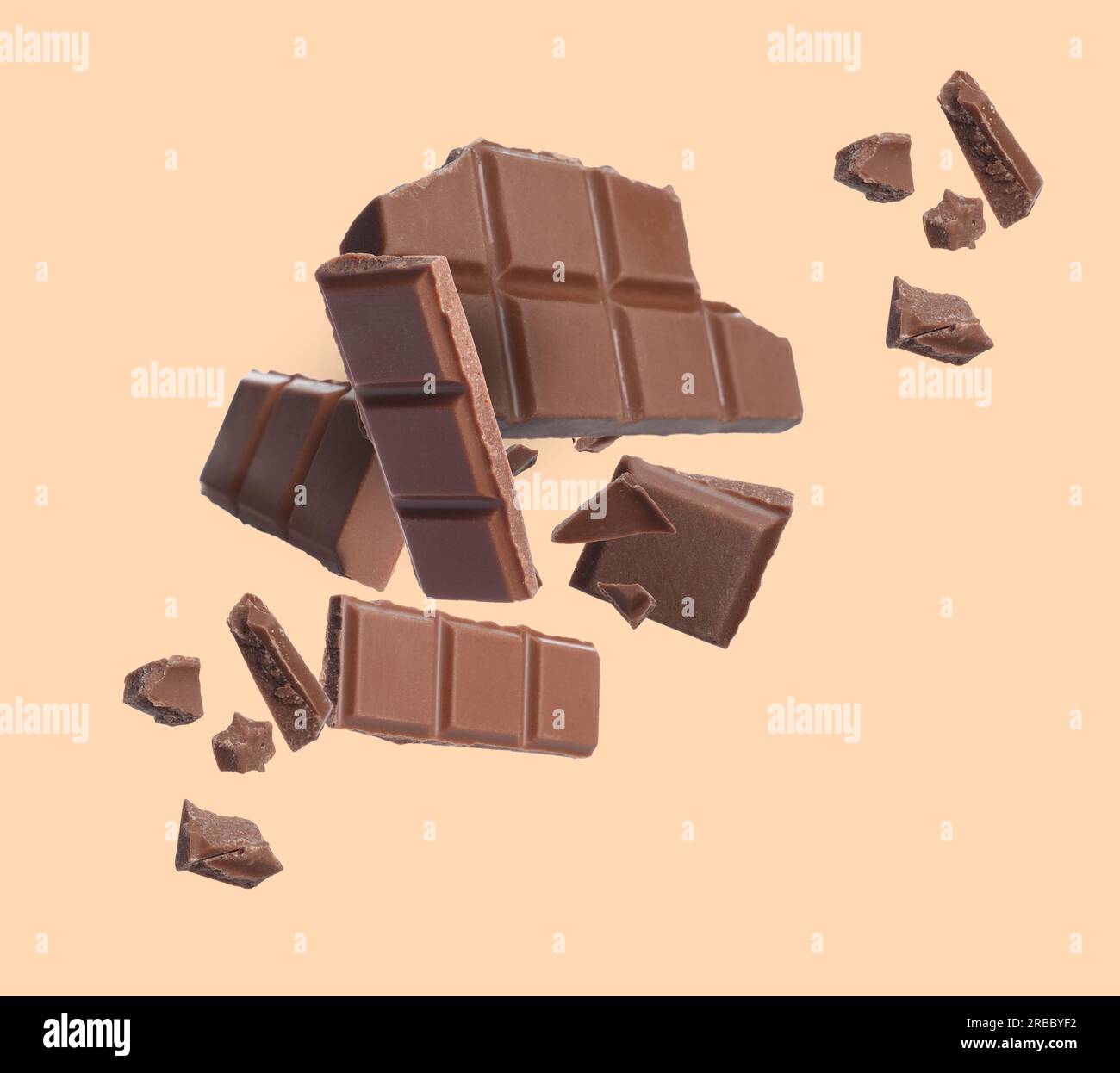 Pieces of chocolate bar falling on beige background Stock Photo - Alamy