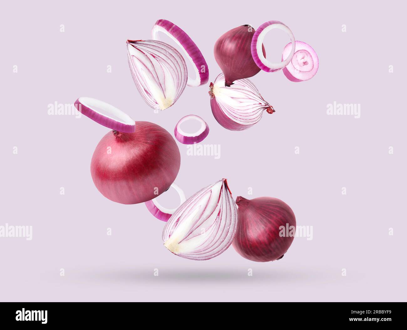 Whole and cut fresh red onions falling on light violet background Stock ...
