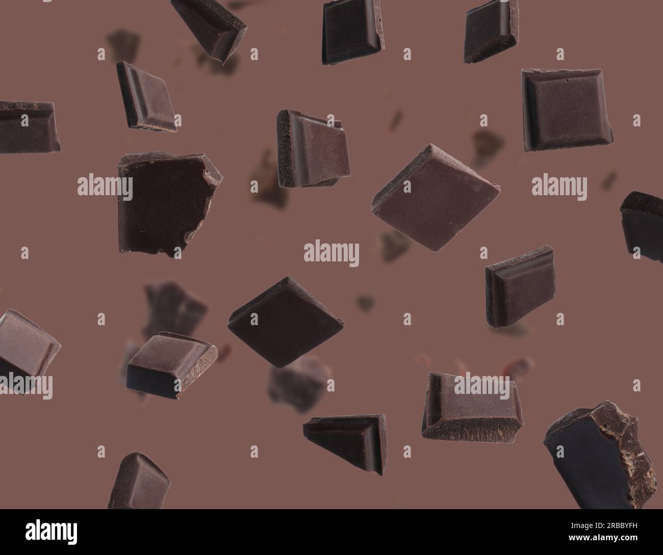 Pieces of chocolate bar falling on brown background Stock Photo - Alamy