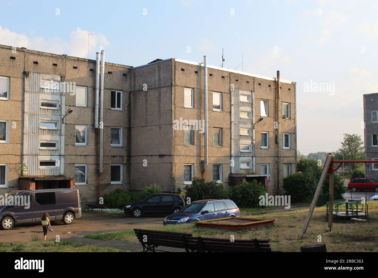 Cars and a girl front of it in front of a Soviet era apartment building ...