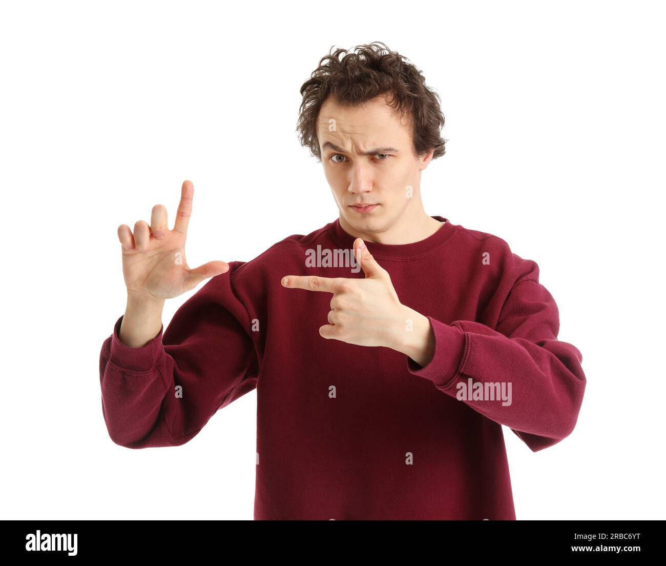 Shocked young man showing loser gesture on white background Stock Photo ...