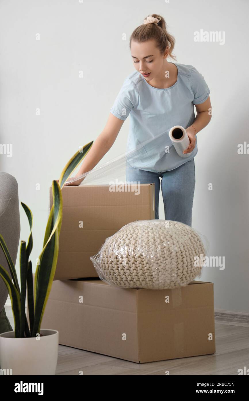 Young woman wrapping cardboard box with stretch film at home Stock ...