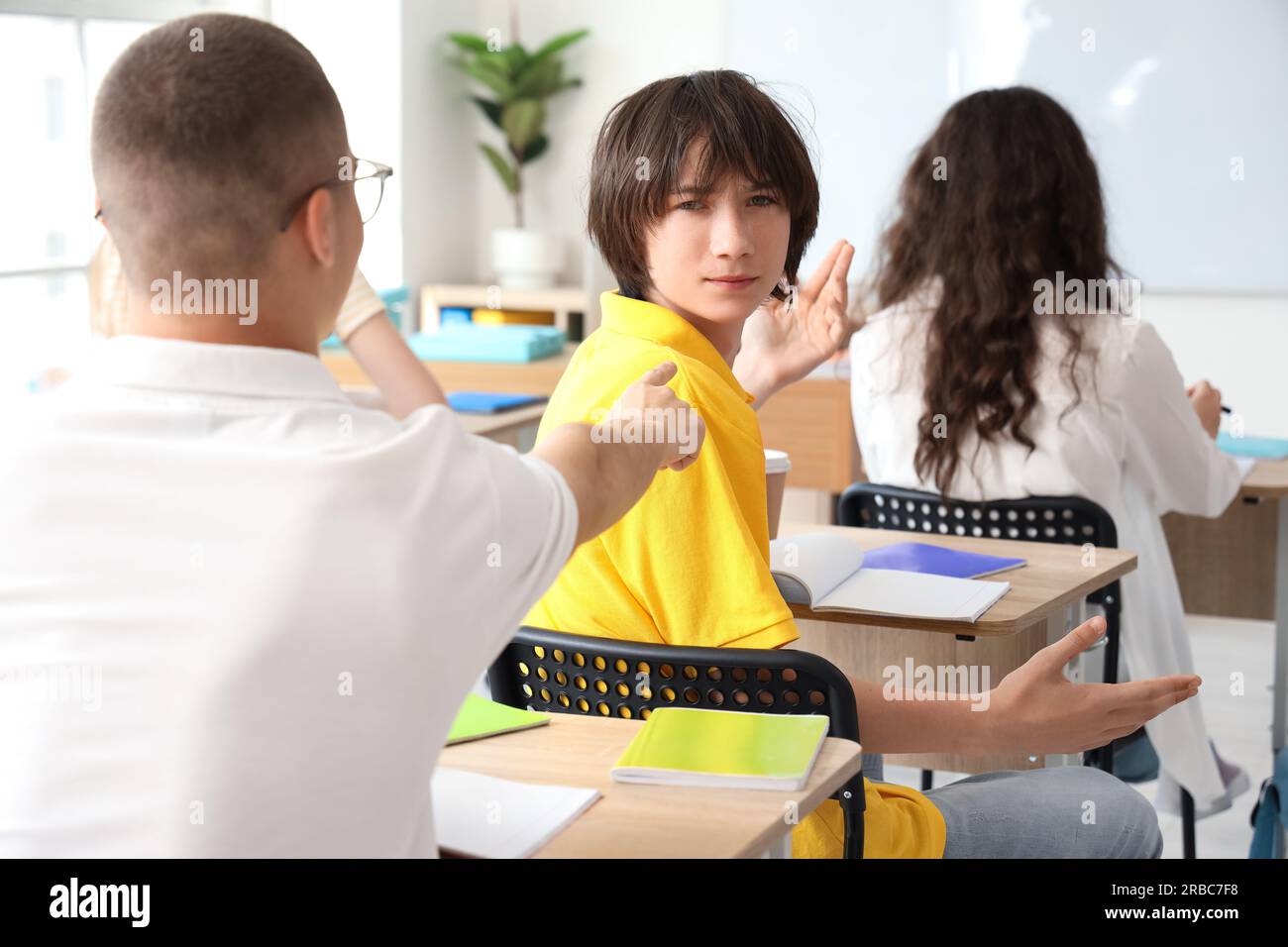 Male student pointing at his classmate during lesson in classroom Stock ...