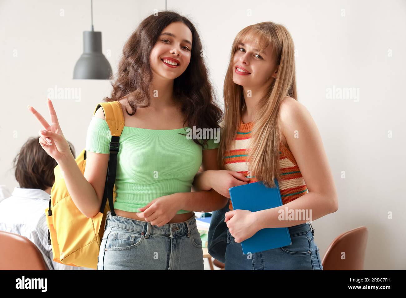 Female students showing victory gesture in room Stock Photo - Alamy