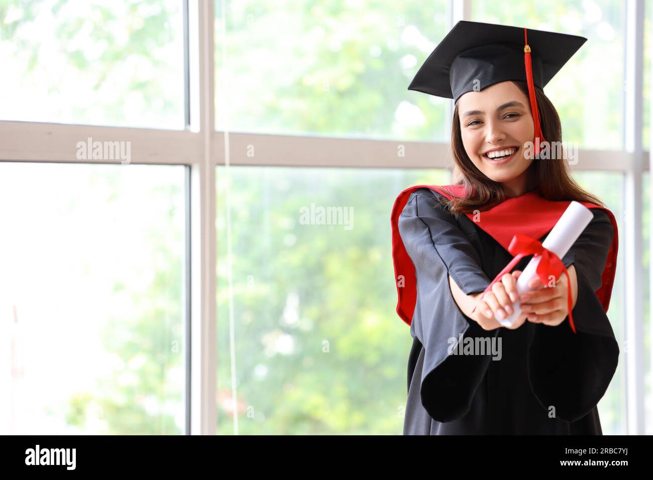 Female graduate student with diploma near window in room Stock Photo ...
