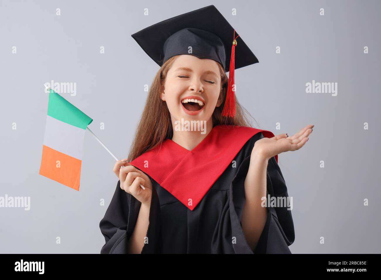 Female graduate student with Irish flag on grey background Stock Photo ...
