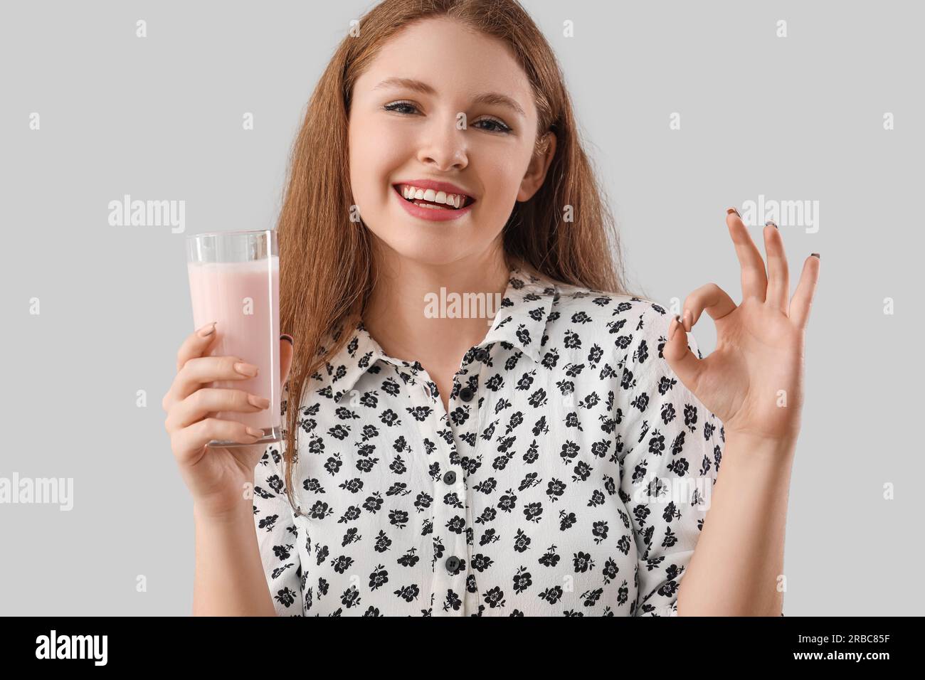 Young woman with tasty yoghurt showing OK on grey background Stock ...