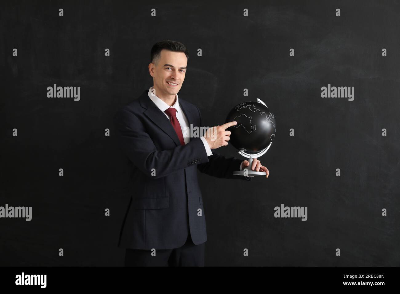 Male Geography teacher with globe near blackboard in classroom Stock ...