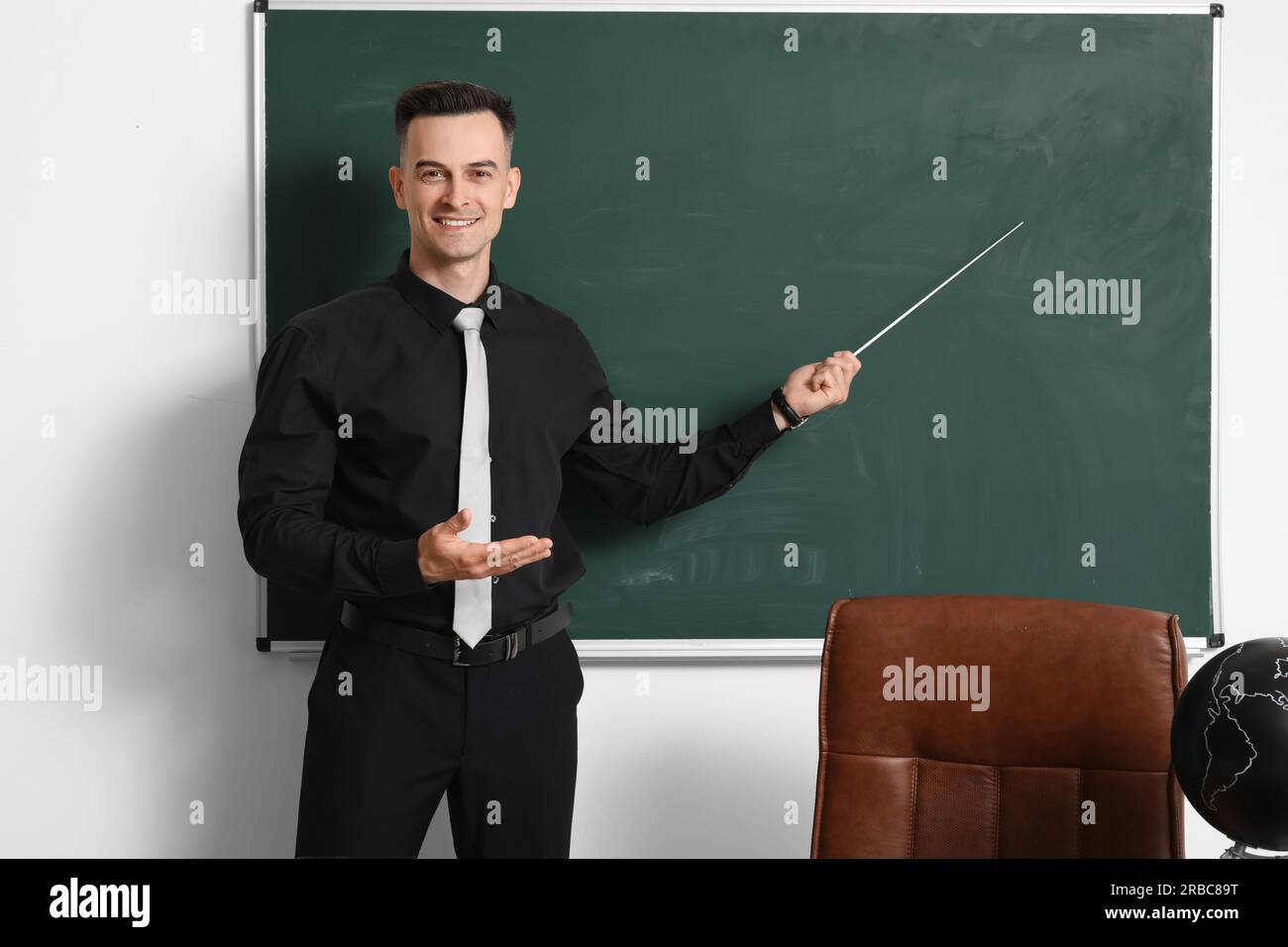 Male teacher with pointer near chalkboard in classroom Stock Photo - Alamy
