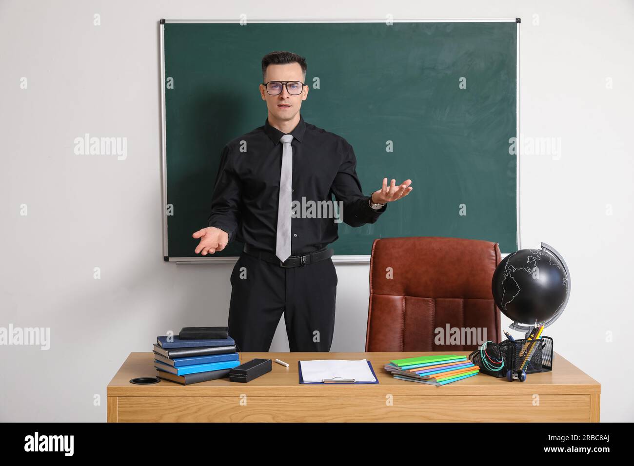 Male teacher conducting lesson near chalkboard in classroom Stock Photo ...
