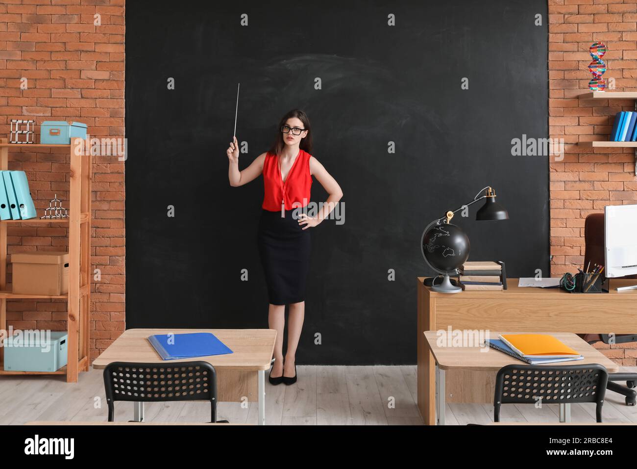 Female teacher with pointer near blackboard in classroom Stock Photo ...