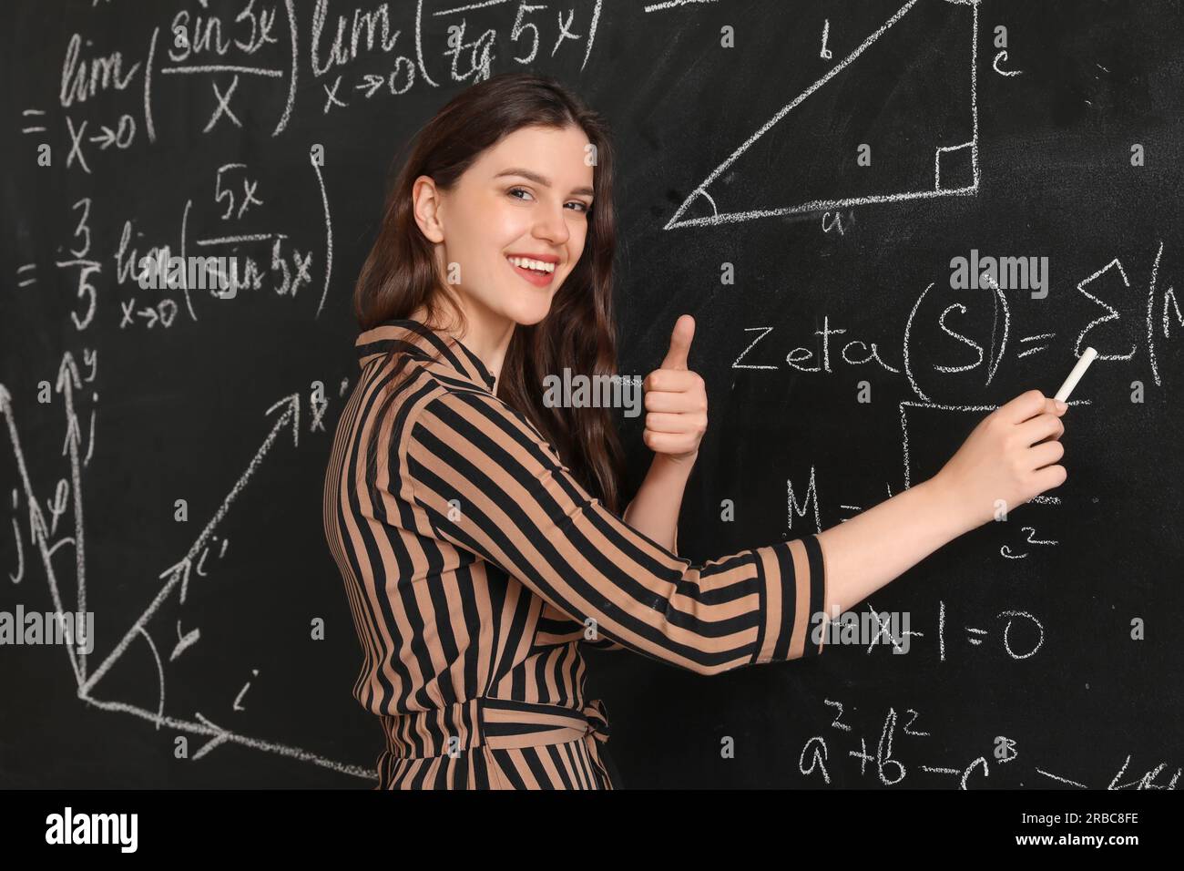 Female Math teacher conducting lesson near blackboard in classroom ...