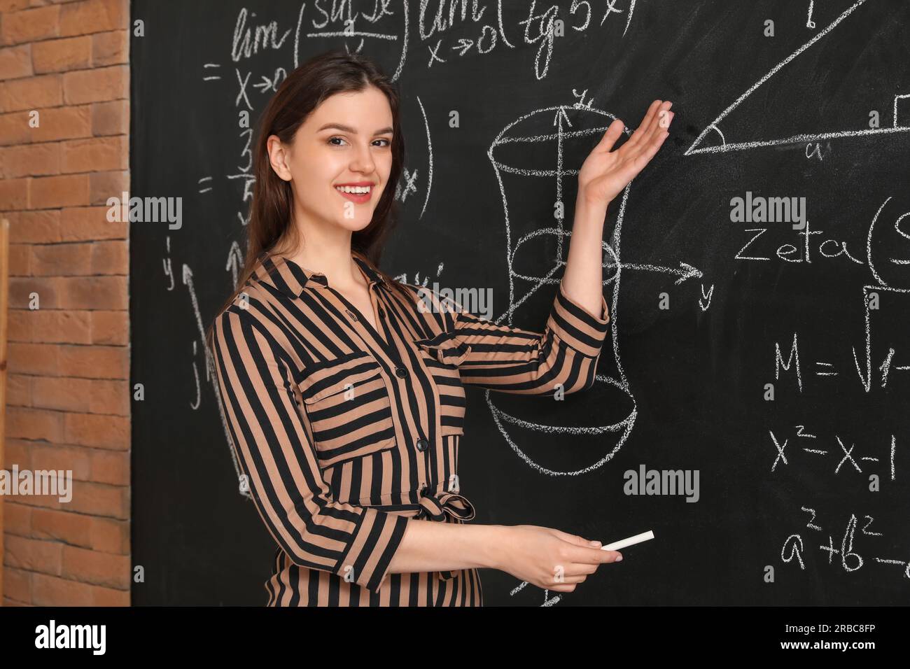 Female Math teacher conducting lesson near blackboard in classroom ...