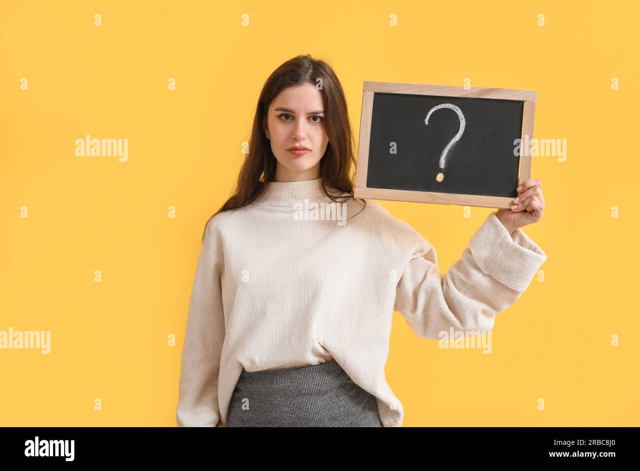 Female teacher holding chalkboard with question mark on yellow ...