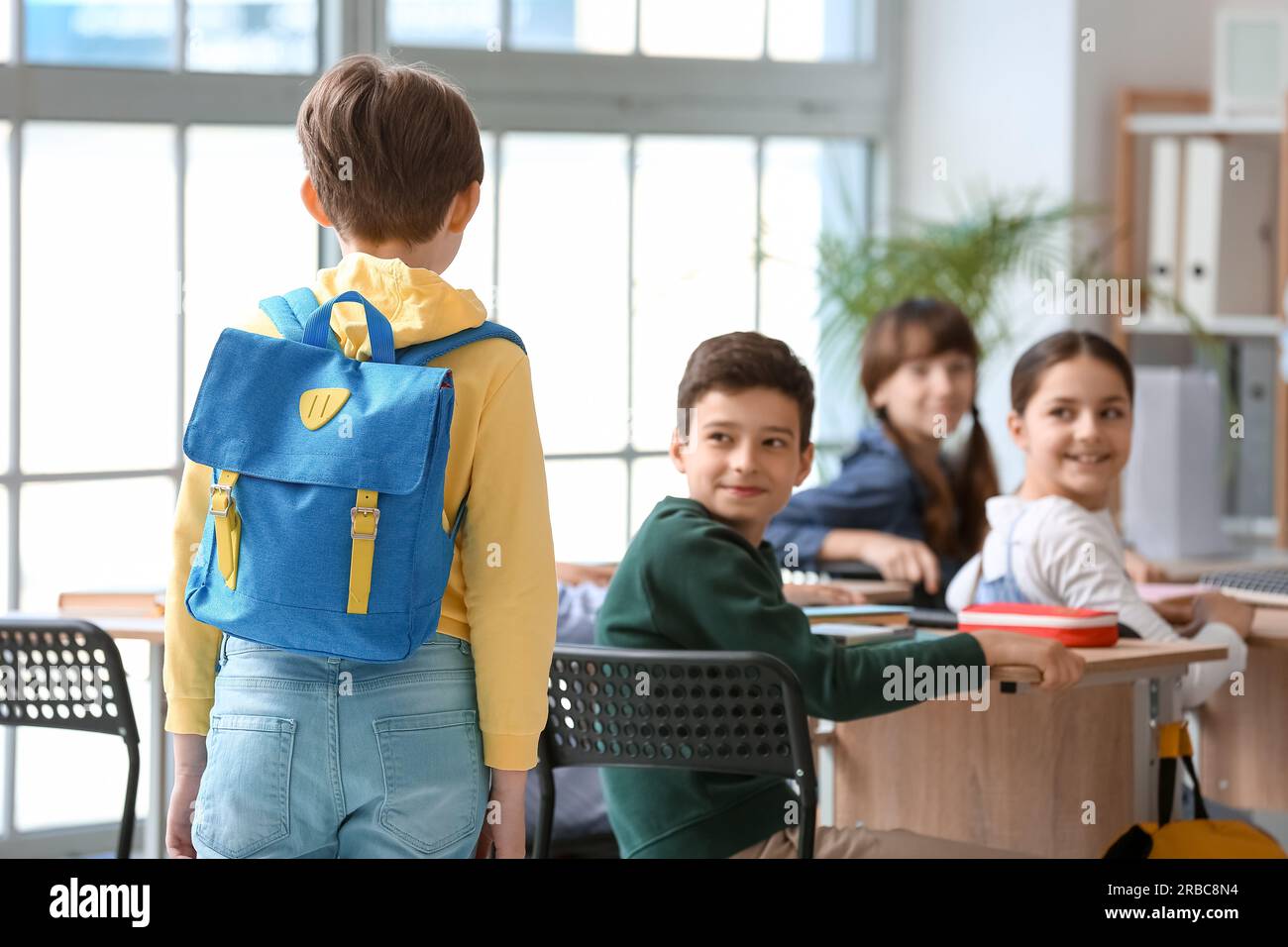 Little boy with backpack in classroom, back view Stock Photo - Alamy