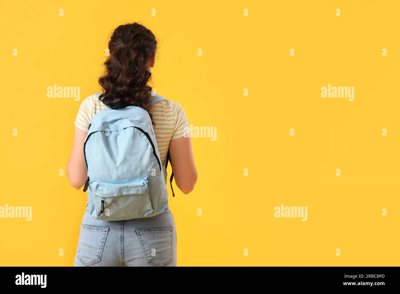 Female student with backpack on yellow background, back view Stock ...