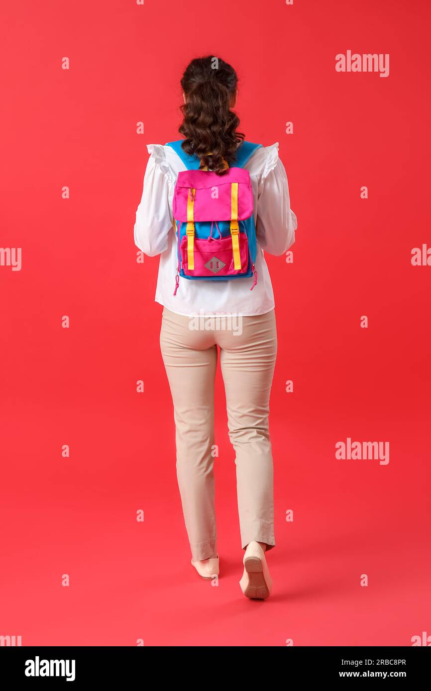 Female student with backpack on red background, back view Stock Photo ...