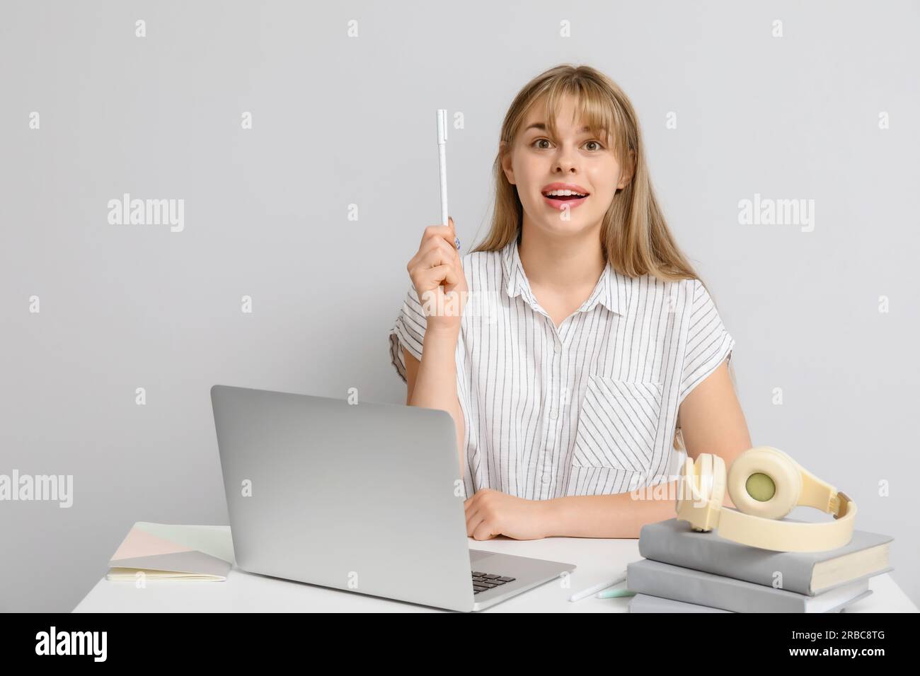 Female student pointing at something on light background Stock Photo ...