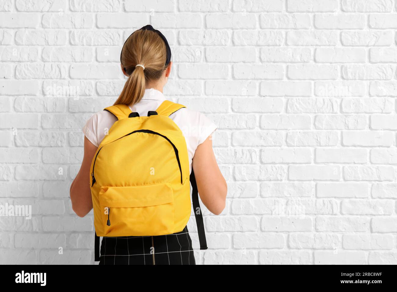 Female student with backpack on white brick background, back view Stock ...