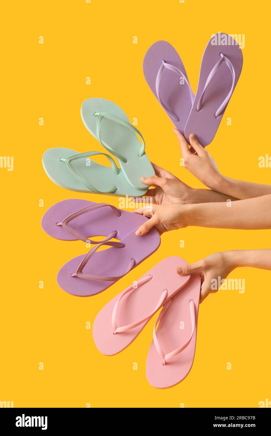 Hands with many different flip-flops on yellow background Stock Photo ...