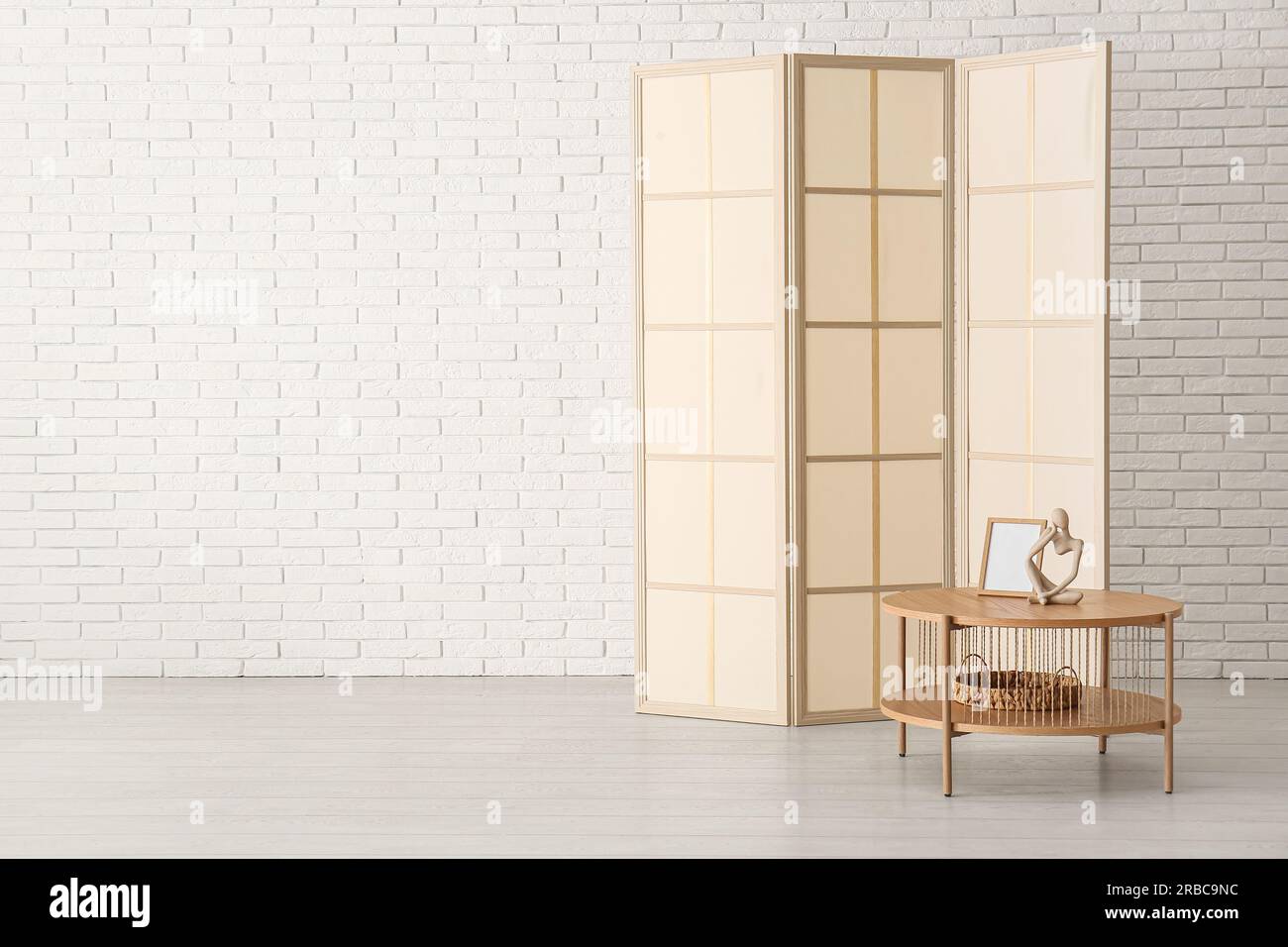 Folding screen and coffee table near white brick wall Stock Photo - Alamy