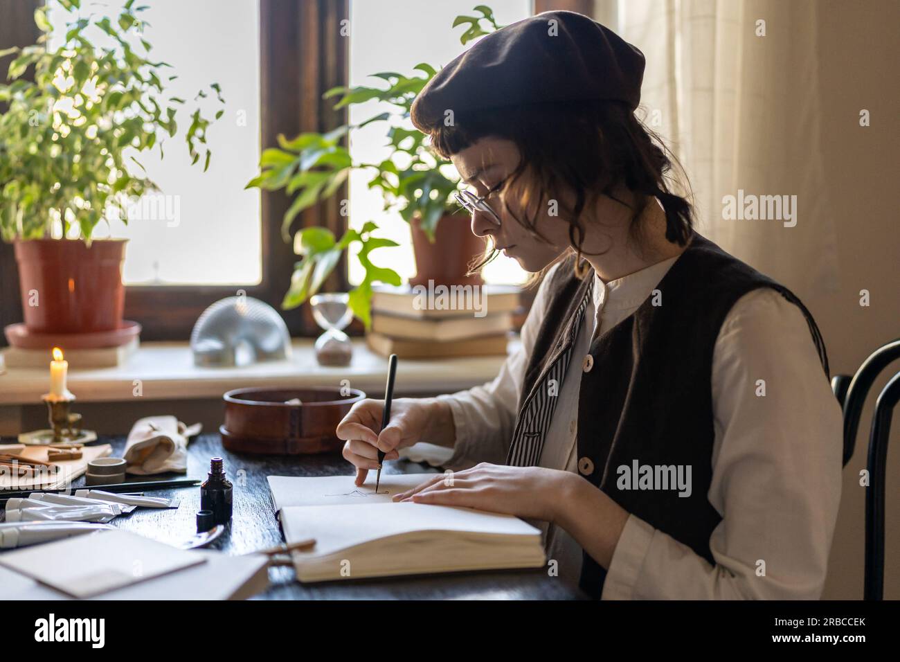 Concentrated illustrator artist young woman draws in notebook in cozy ...