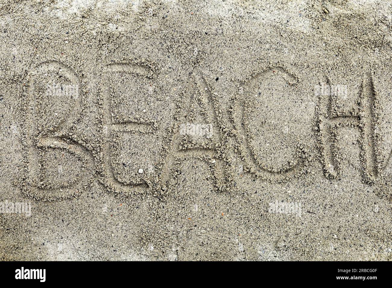 Handwritten word of beach on sand at the beach Stock Photo - Alamy