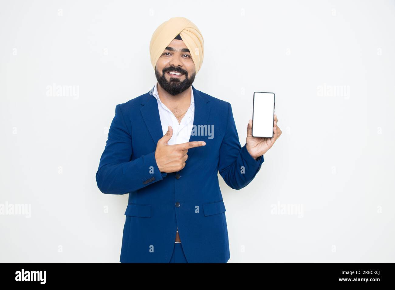Happy young indian sikh businessman wearing suit pointing at smart ...