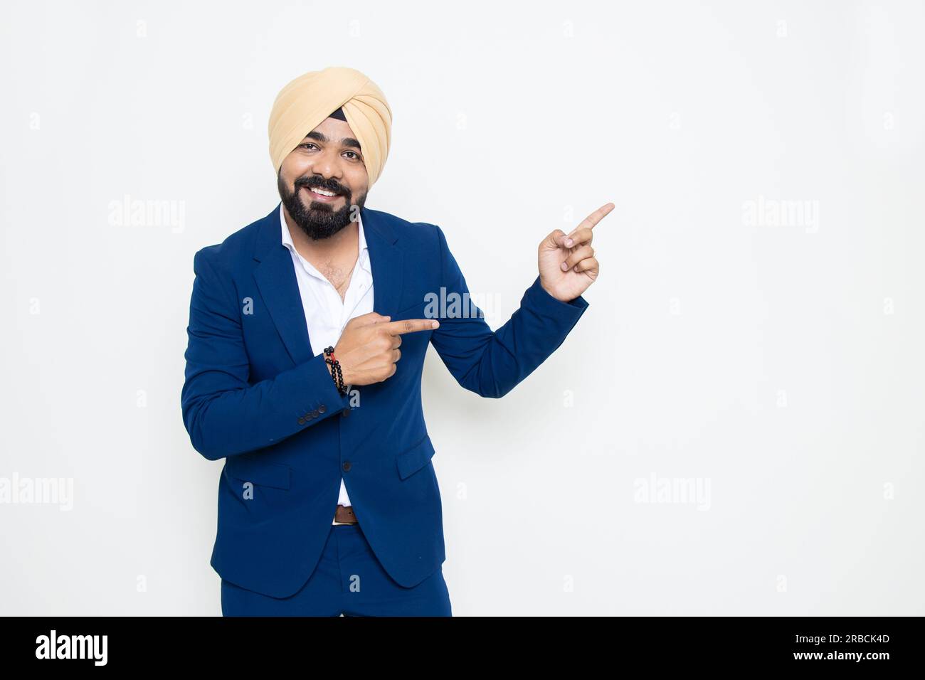 Happy indian sikh businessman wearing suit pointing at blank space ...