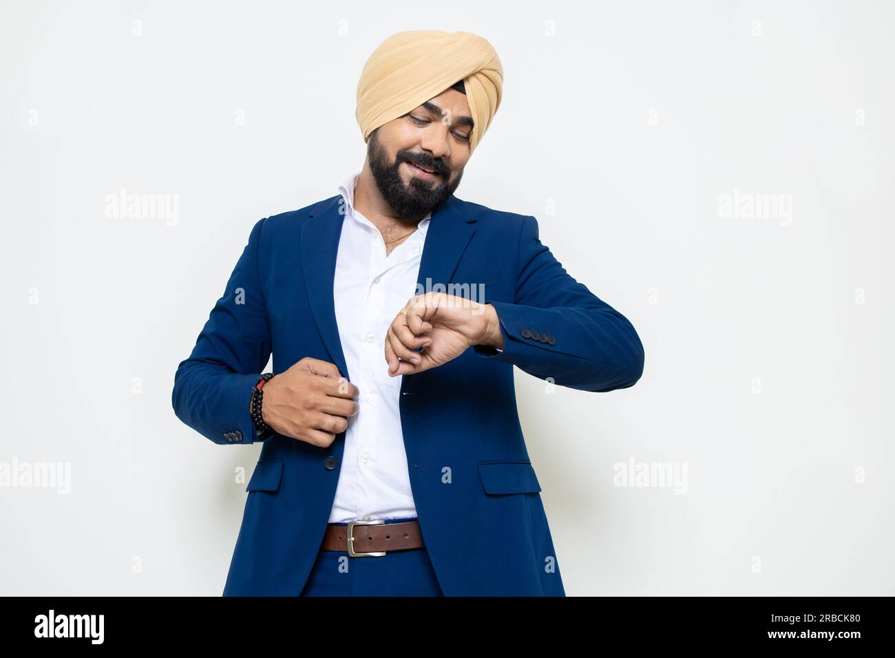Young indian sikh businessman wearing suit looking at his wristwatch ...