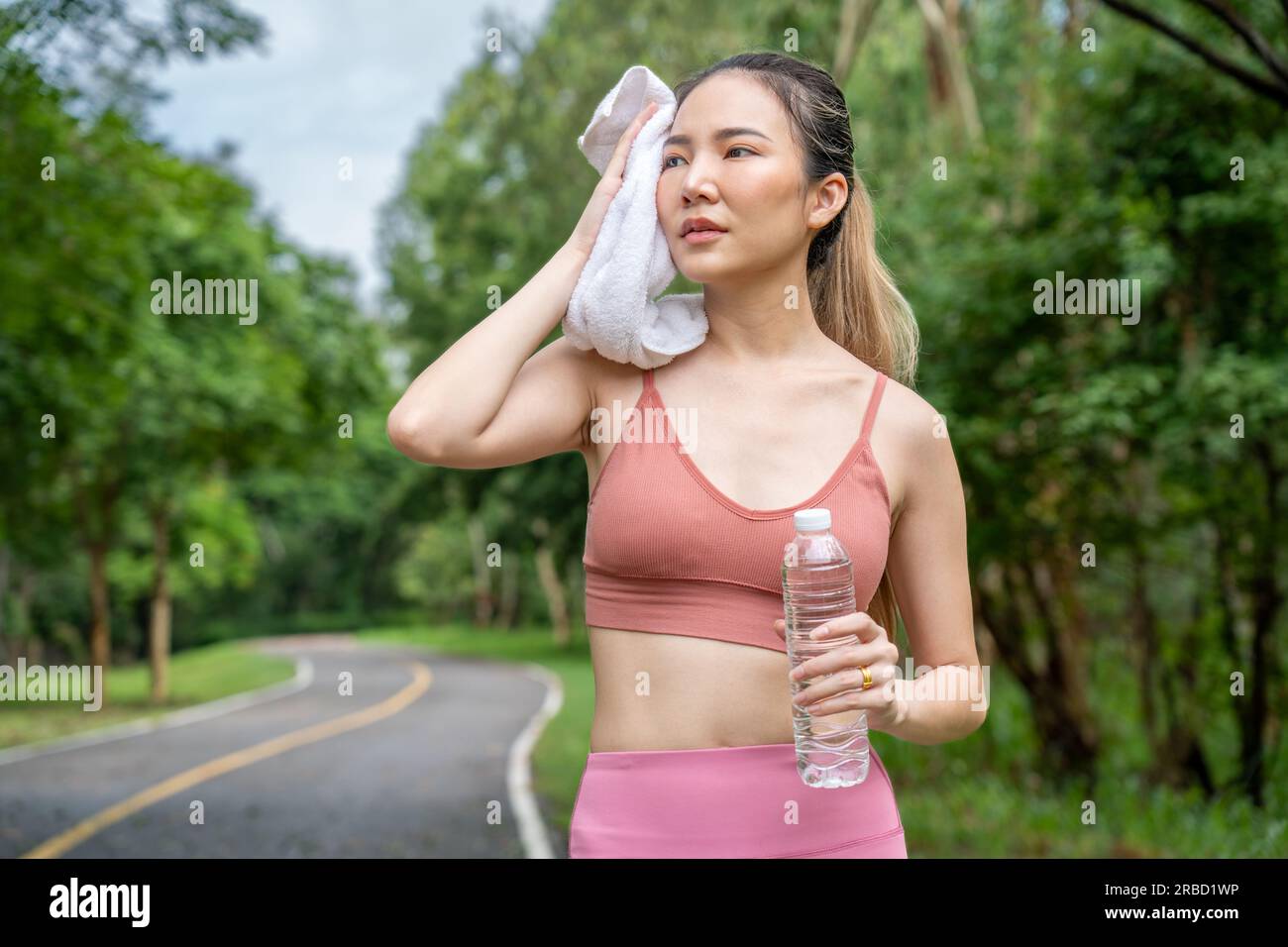 Young attractive Asian woman wiping off her sweat from her forehead ...