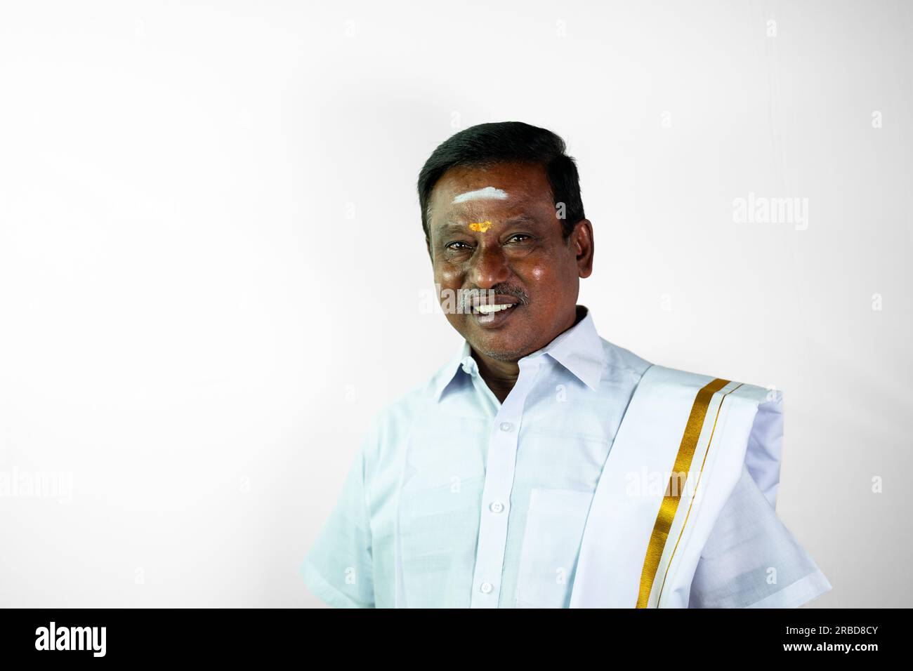 A smiling South Indian man in his traditional dress, a white dress ...