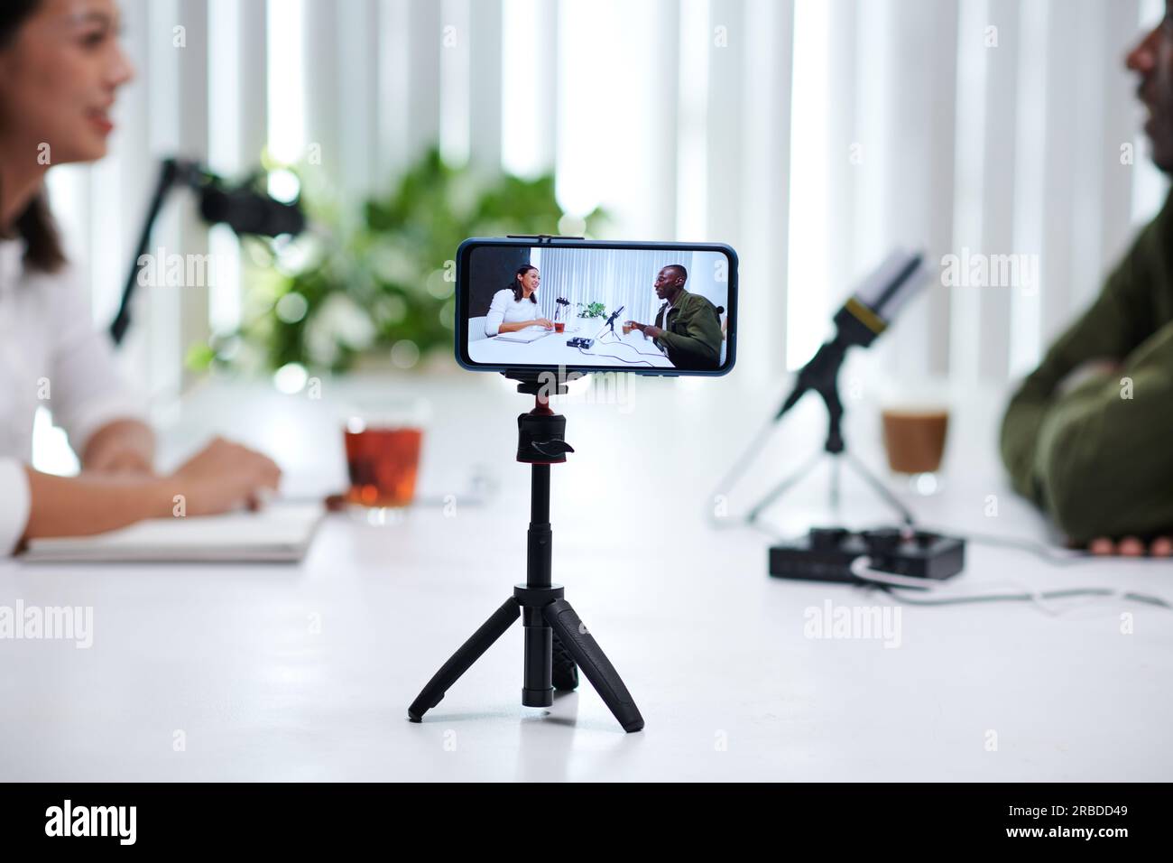 Smartphone recording podcaster talking to guest at big table Stock ...