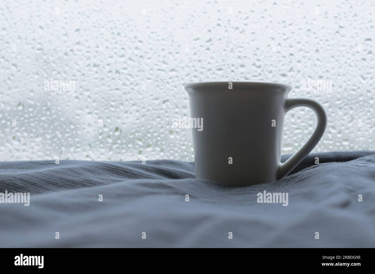 A cup of Espresso coffee shot puts on bed with rain drop on window in ...
