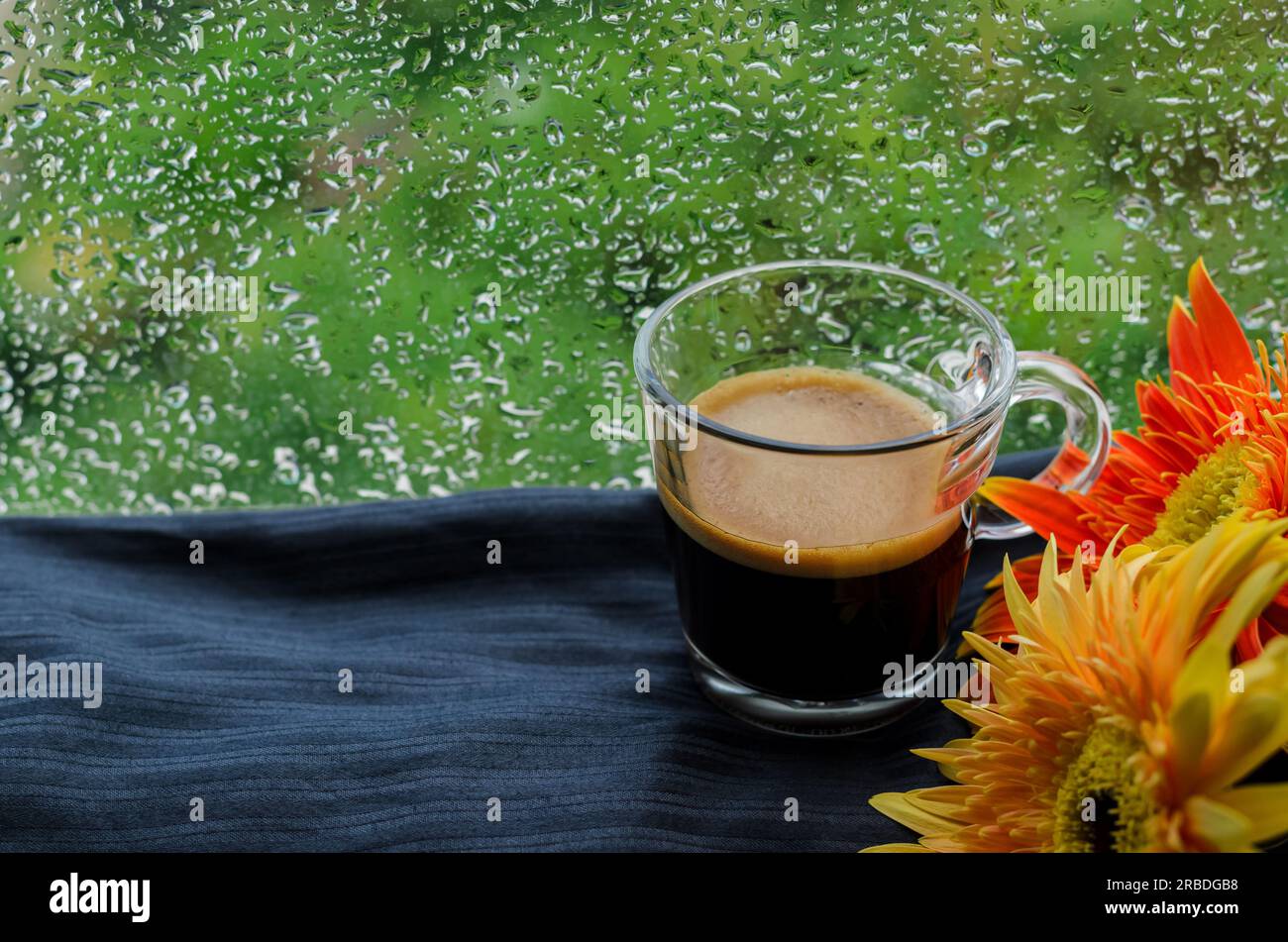 A glass of Espresso coffee shot puts on bed with Gerbera flowers when ...