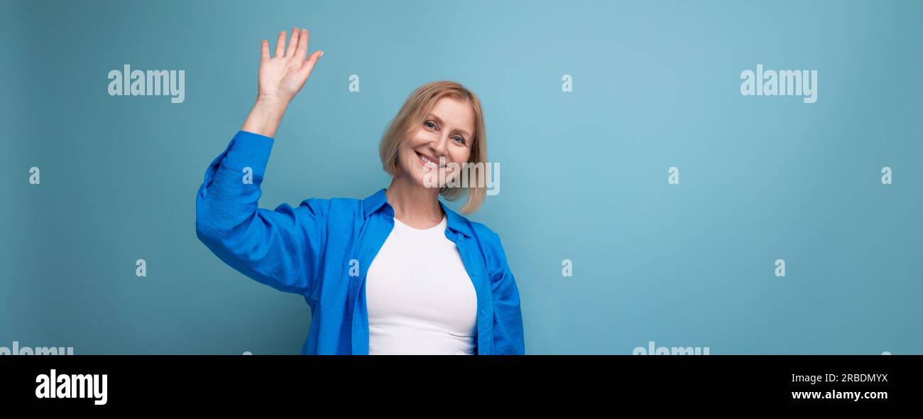 smiling blonde middle-aged woman with bob haircut on studio background ...