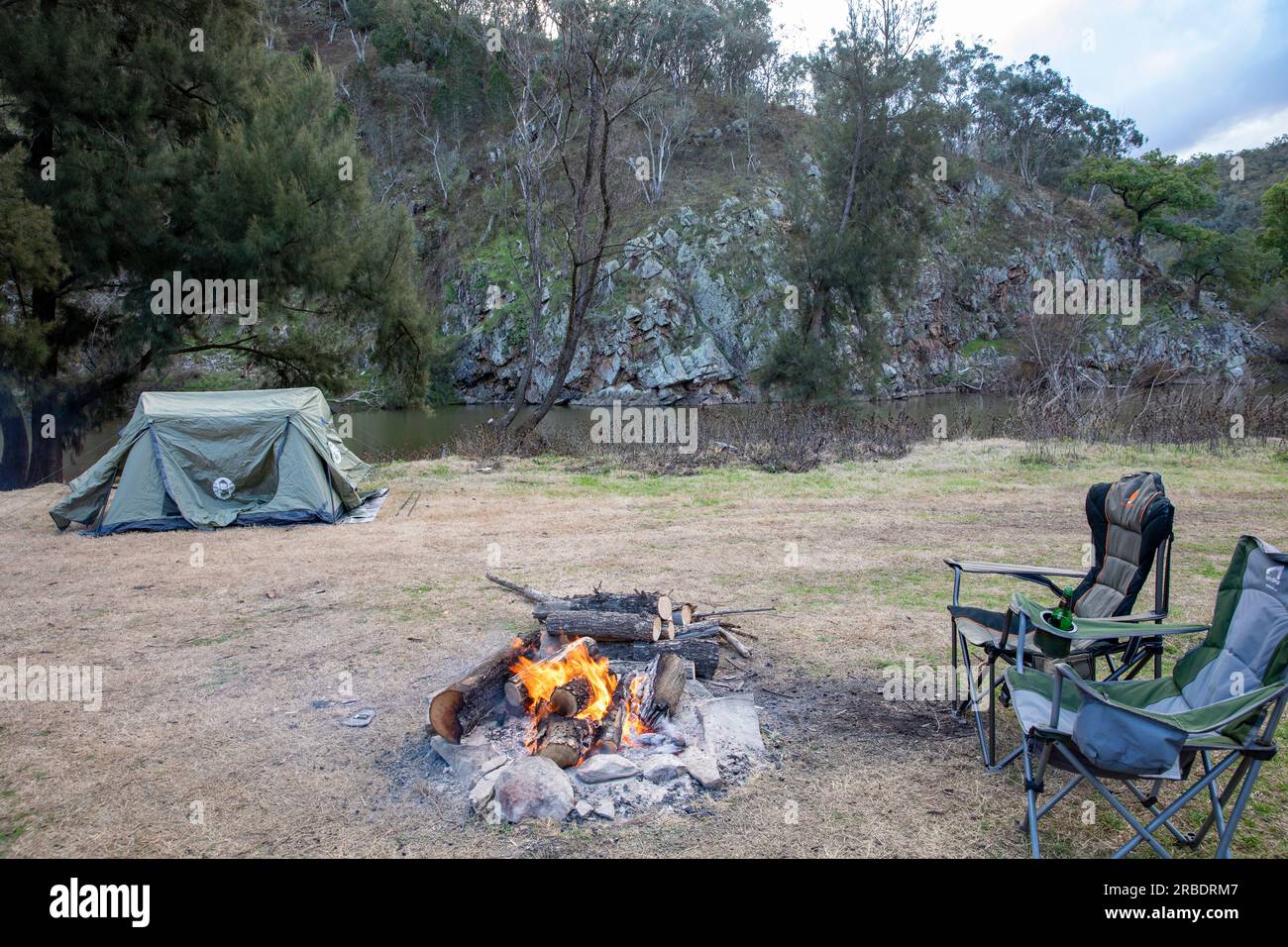 Camp fire and camping chairs and tent beside the Macquarie River on ...