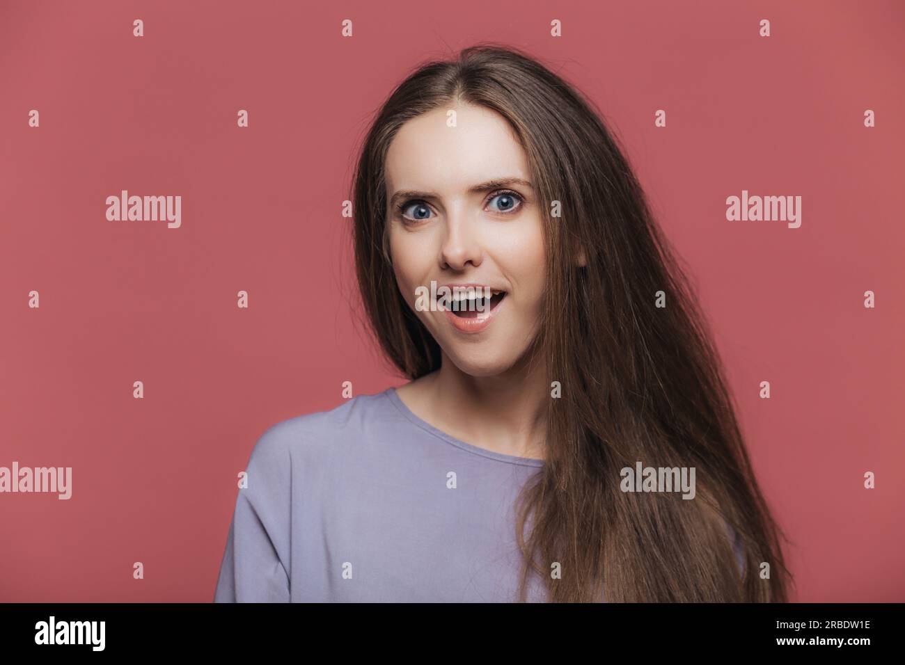 Amazed model with dark hair, open mouth, hears unexpected news. Pink ...
