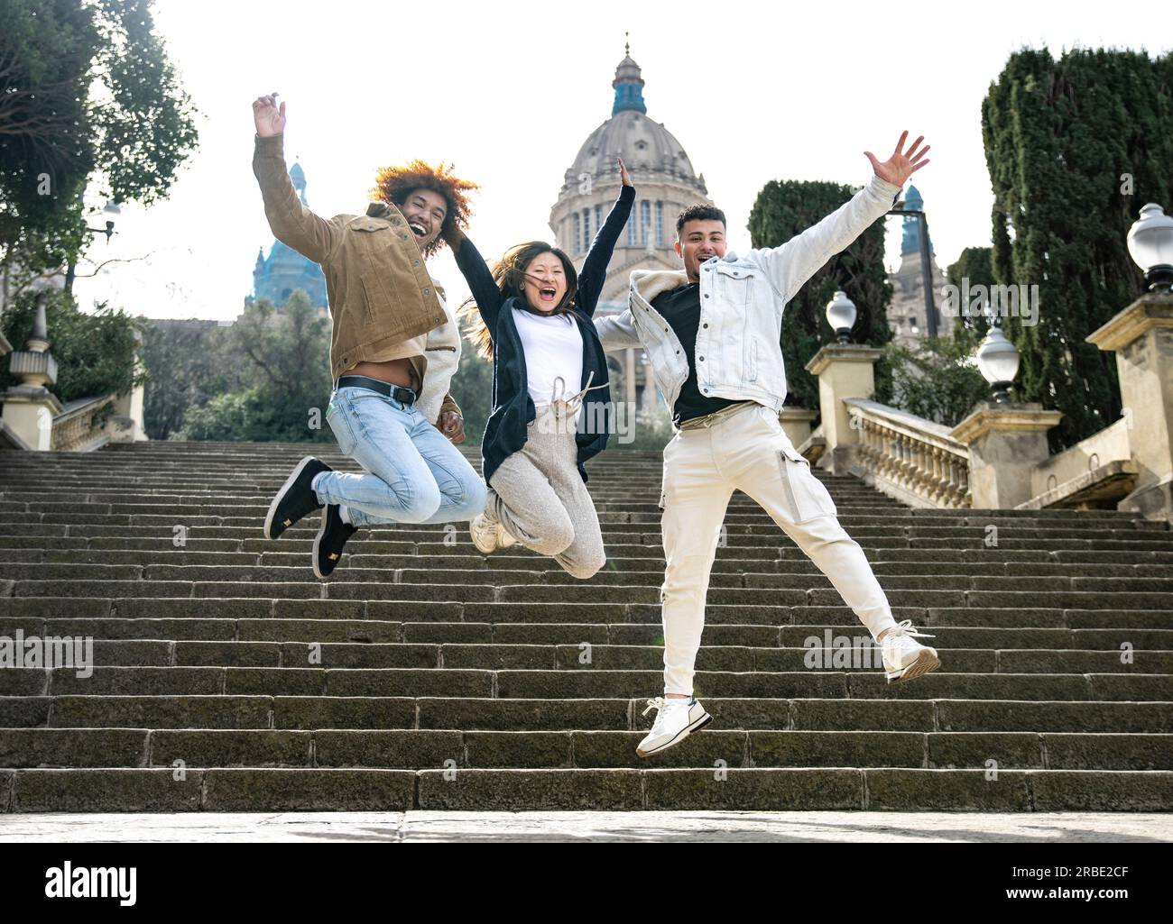 Three young diverse people jumping on a stairs. Multiracial group of ...