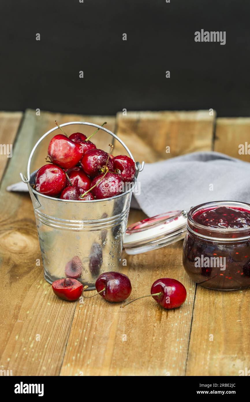 Some delicious ripe cherries inside a metal bucket and red fruit jam in ...