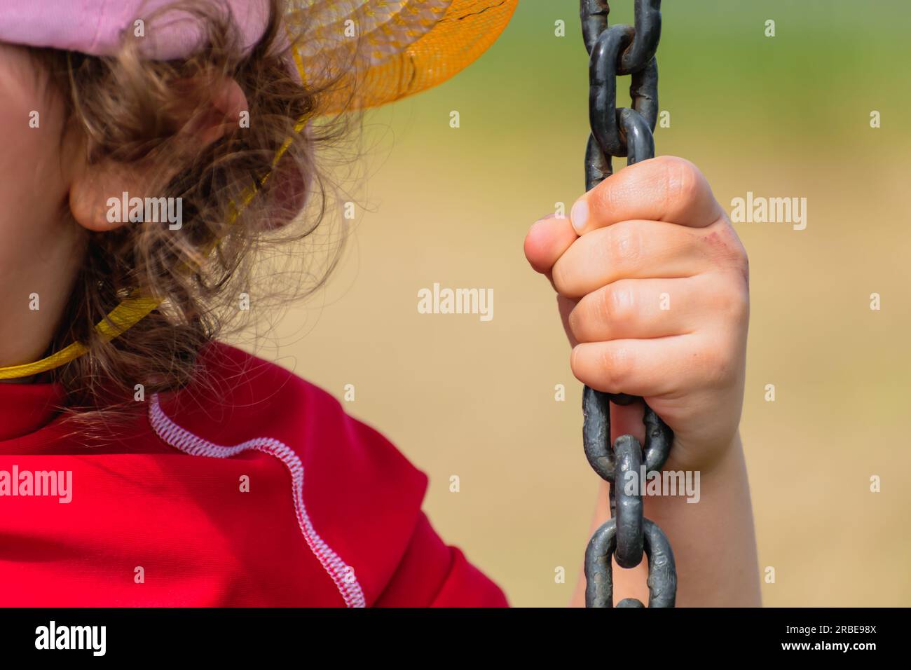 Close-up on a baby’s hand holding a chain, kid having fun playing on a ...
