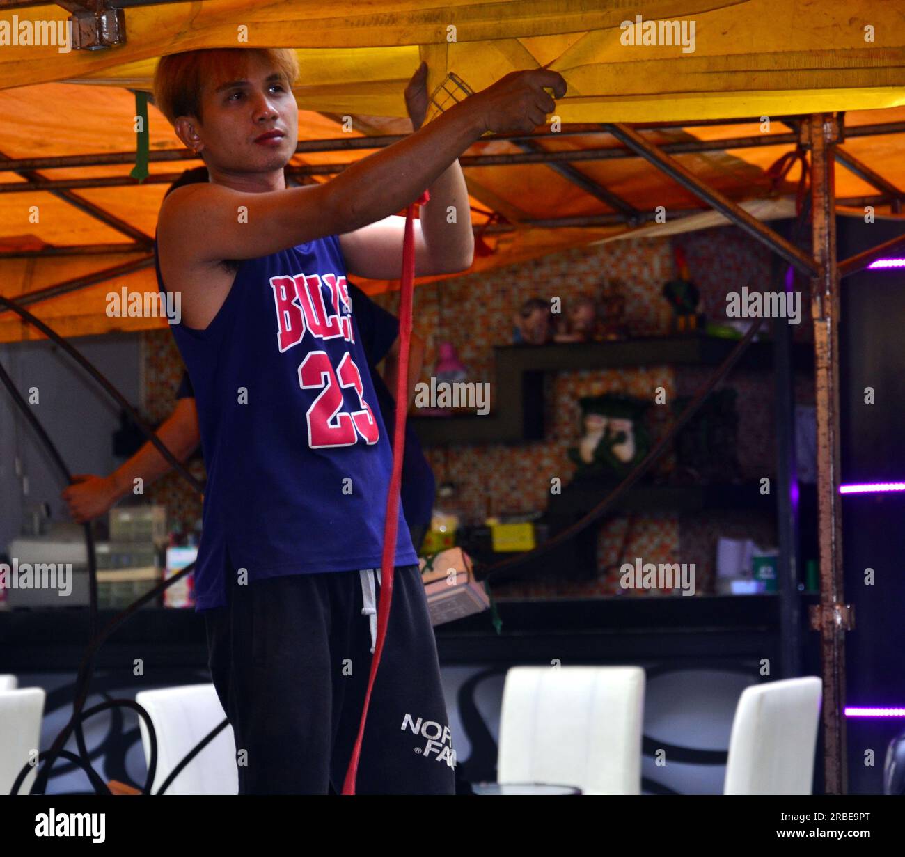 A young man is part of a team of men who assemble the stall structures ...